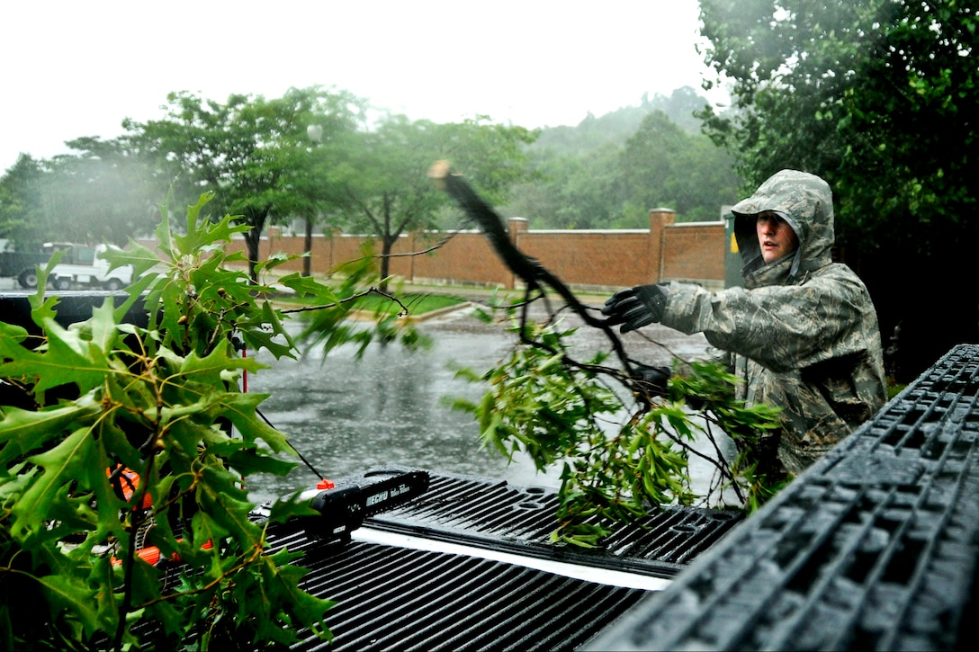 Air Force Senior Airman Joshua Garner cleans up tree branches knocked ...