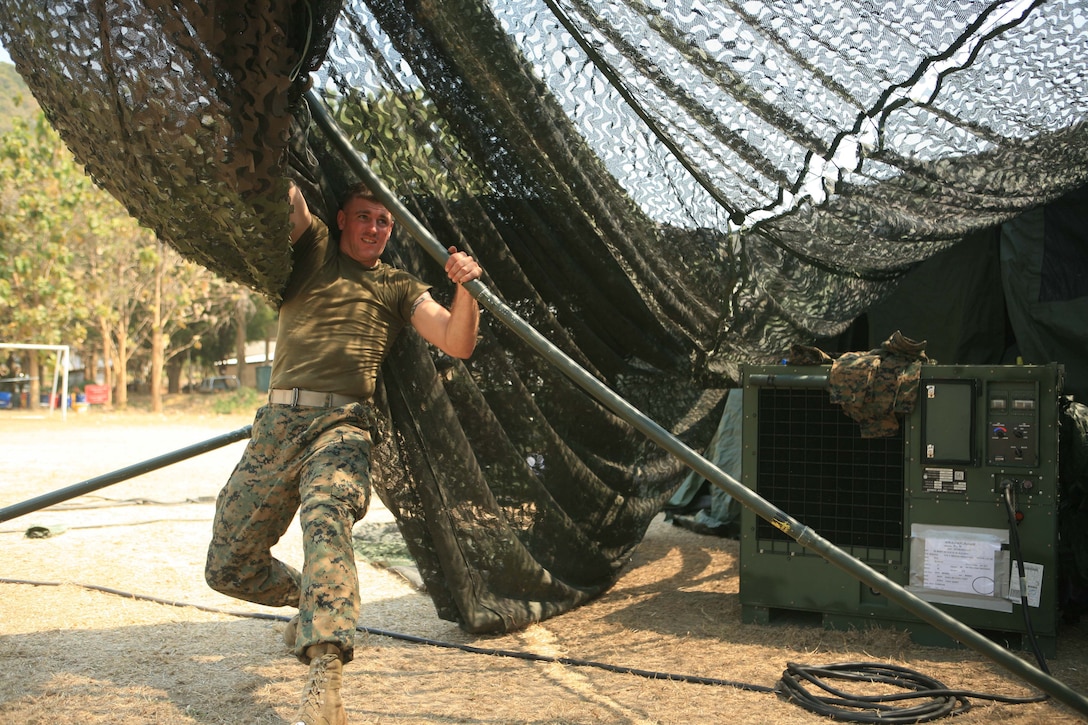 U.S. Marine Corps Lance Cpl. Joshua Sorensen sets up camouflage netting ...