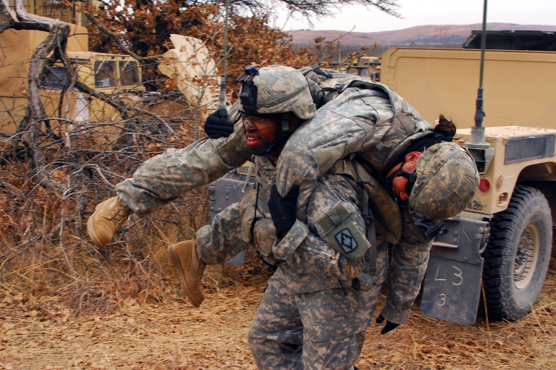 A U.S. Army soldier carries a simulated wounded soldier to a casualty ...