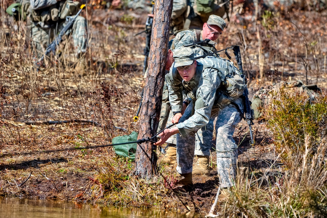 U.S. Army Ranger students secure a rope to a tree as part of the rope ...