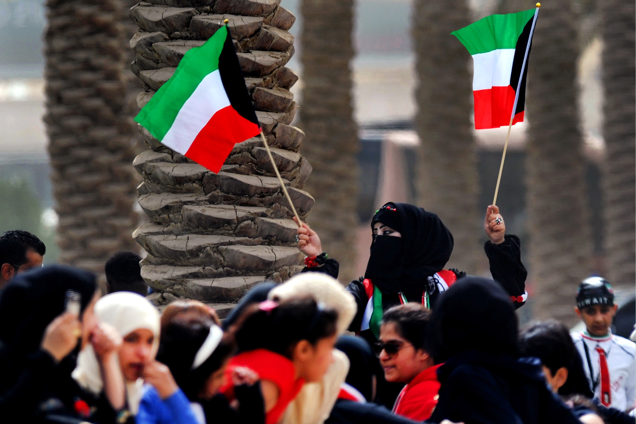 A woman waves two Kuwaiti flags during a military demonstration held at ...
