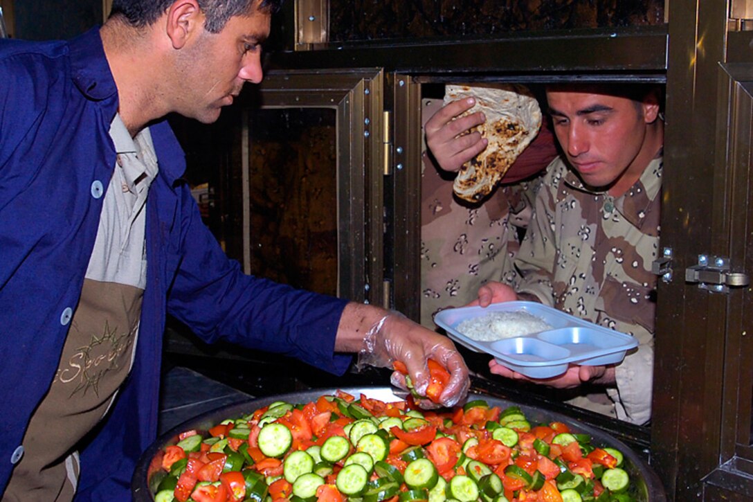 Iraqi army soldiers receive dinner rations of cucumbers and tomatoes ...
