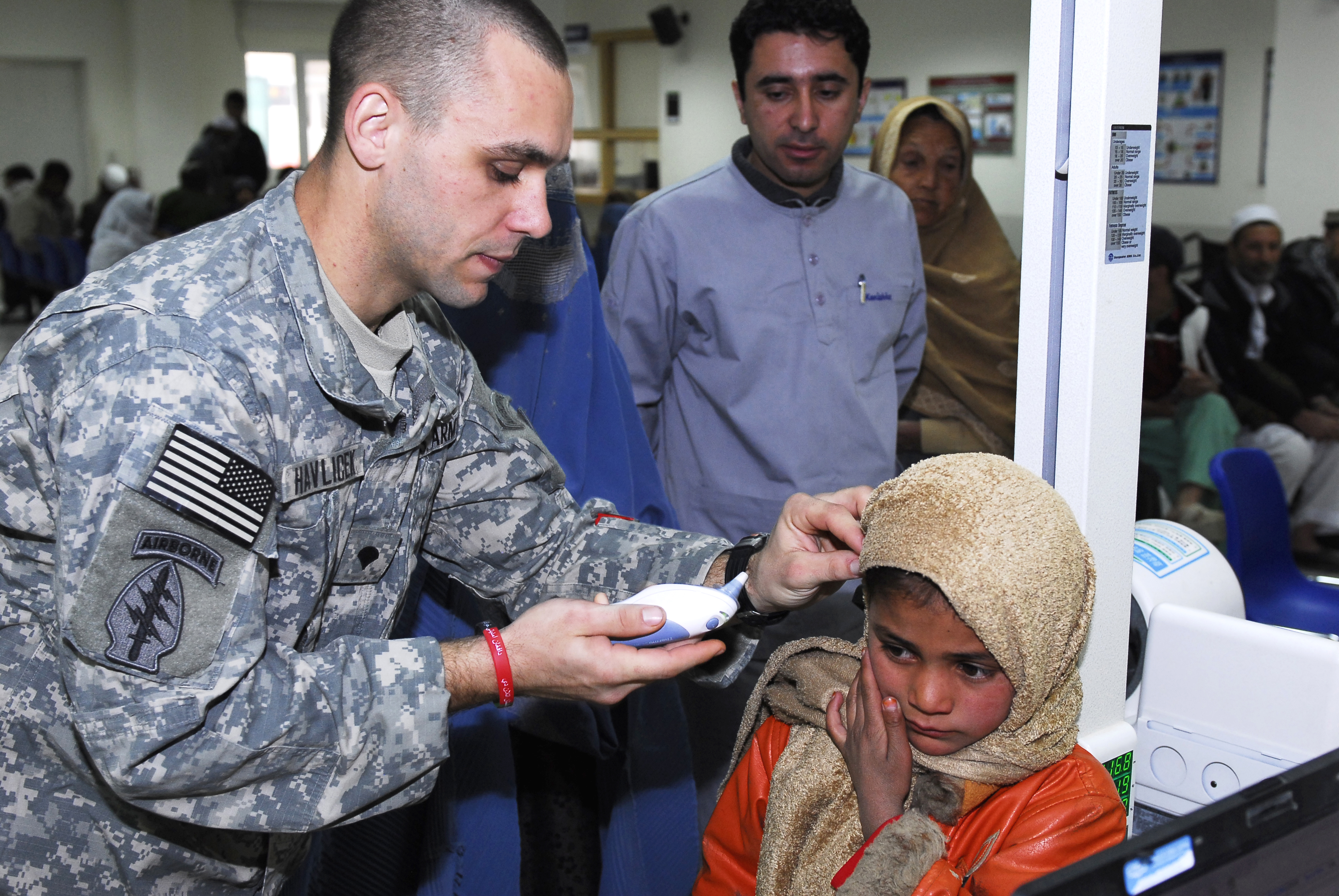 U.S. Army Spc. David Havlicek takes the temperature of a young girl at ...
