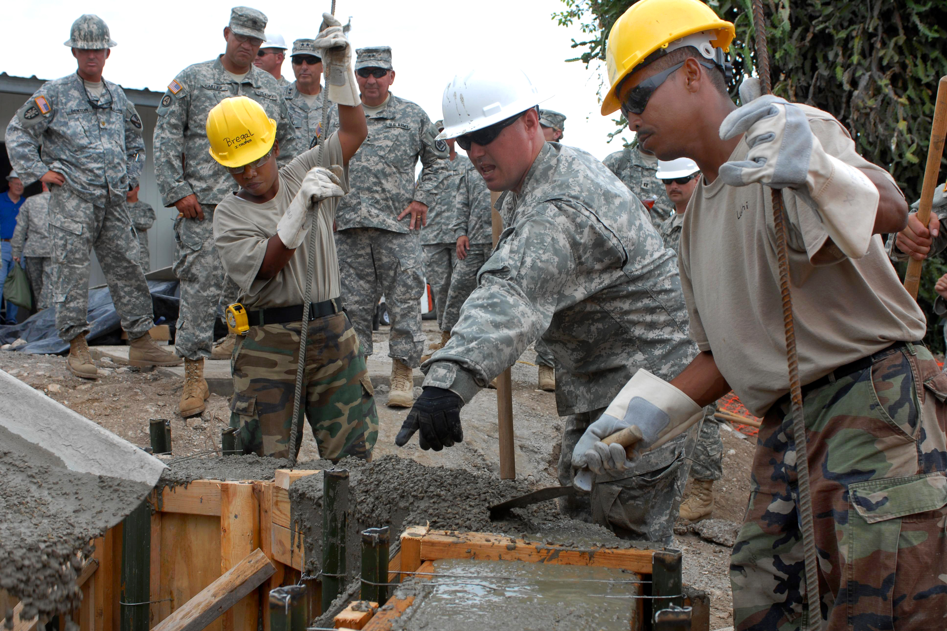 U.S. Army Sgt. Daryl Ayers, center, directs concrete mixer truck ...