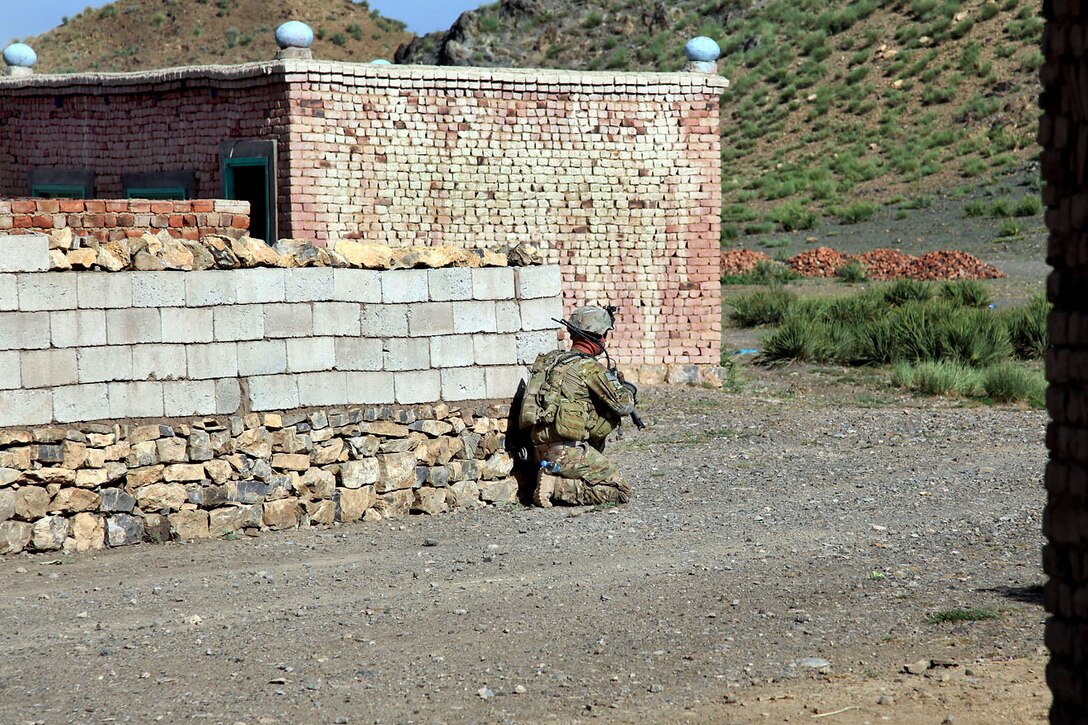 U.S. Army Sgt. Ryan Kennedy kneels to secure his location during a ...