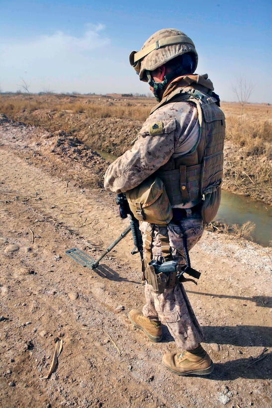 U.S. Marine Sgt. Robert Torres uses a metal detector as he sweeps the ...