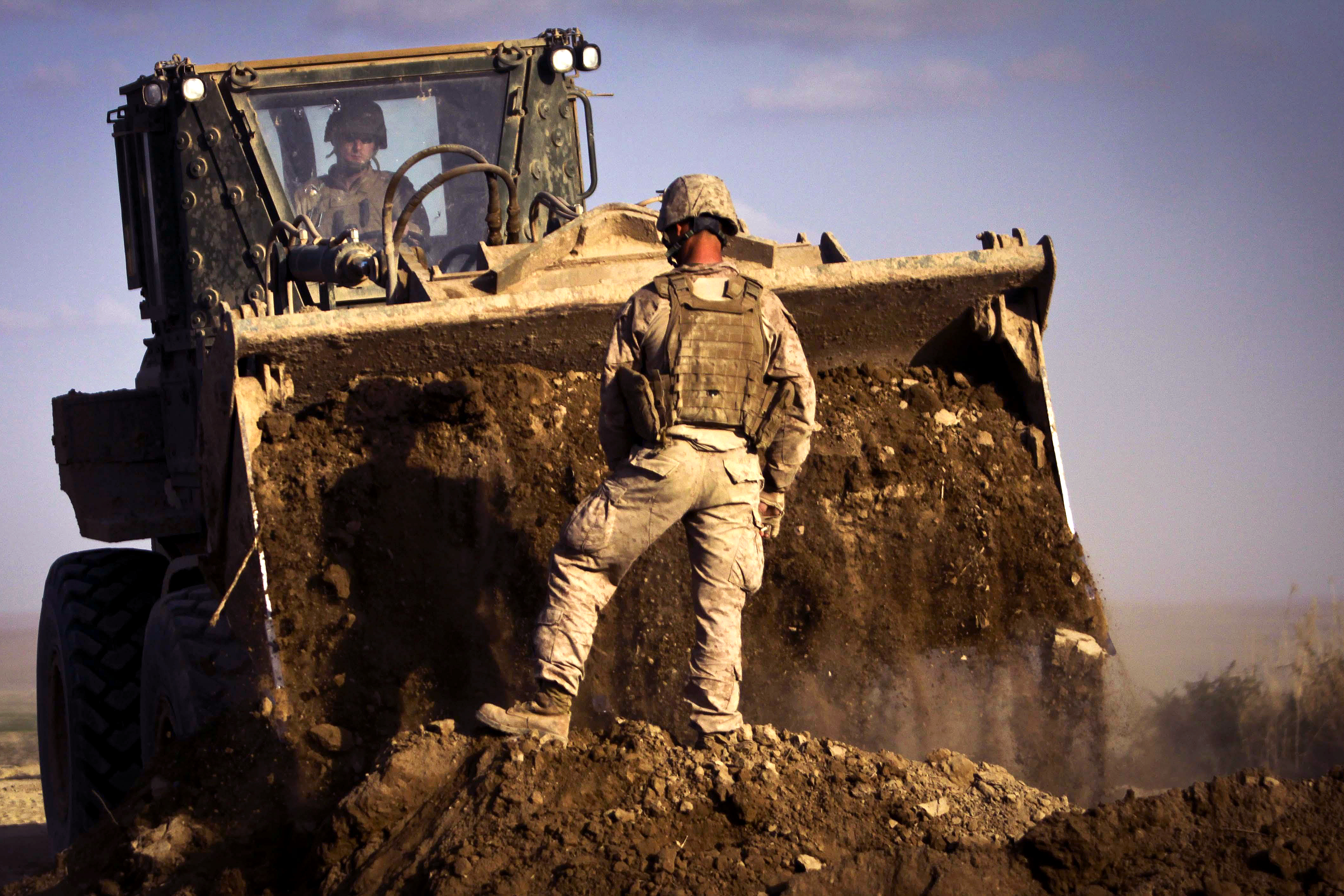 U.S. Marine Corps Lance Cpl. Steven Reese guides a heavy equipment ...