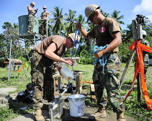 U.S. Navy Seabees fill water buckets to use in the Muya engineering ...