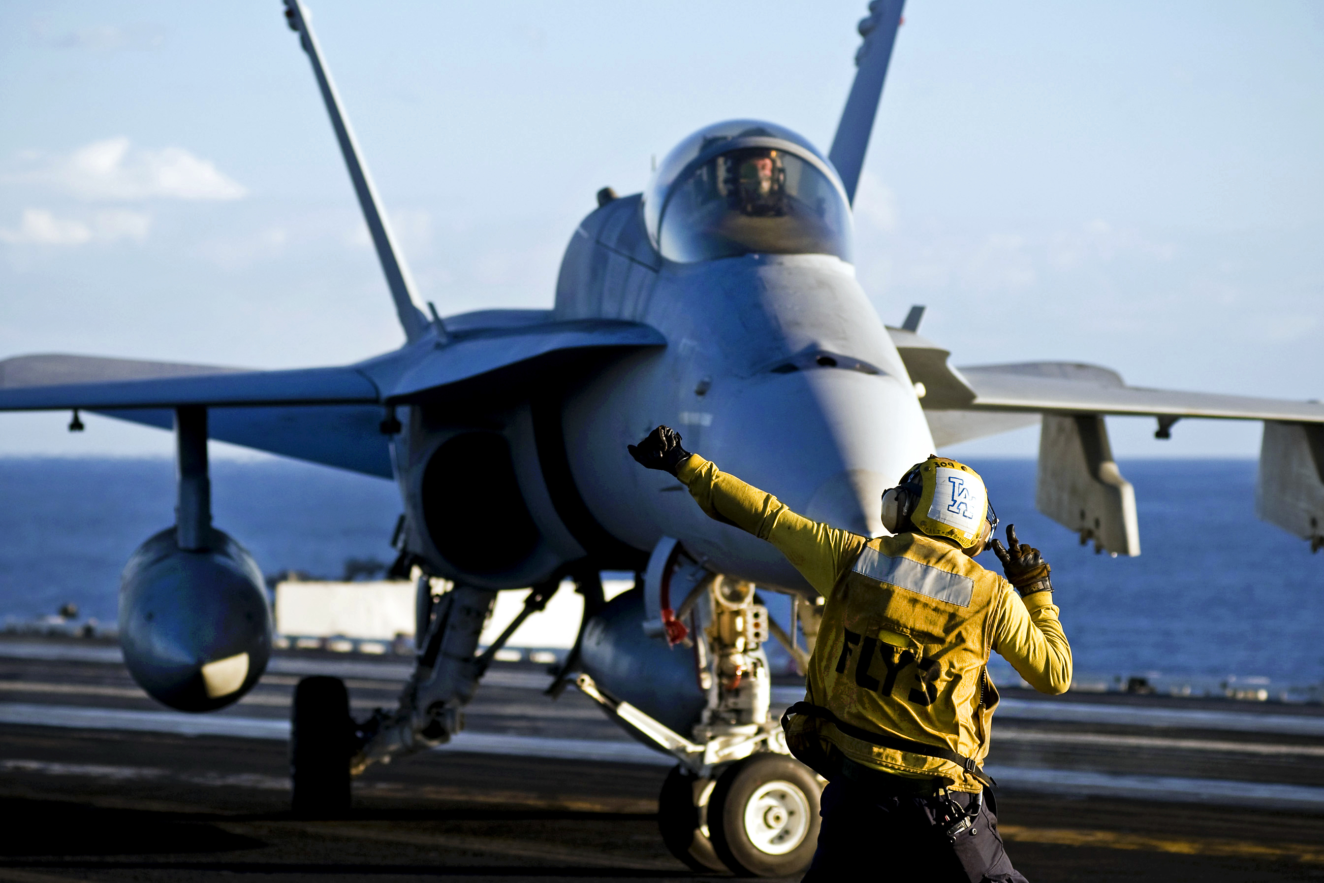 U.S. Navy Petty Officer 3rd Class Sean Pennala directs an F/A-18C ...