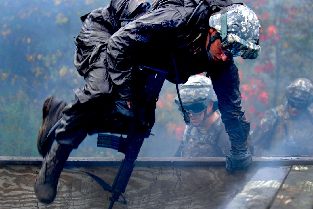 A soldier vaults over a wall to secure a village during premobilization ...