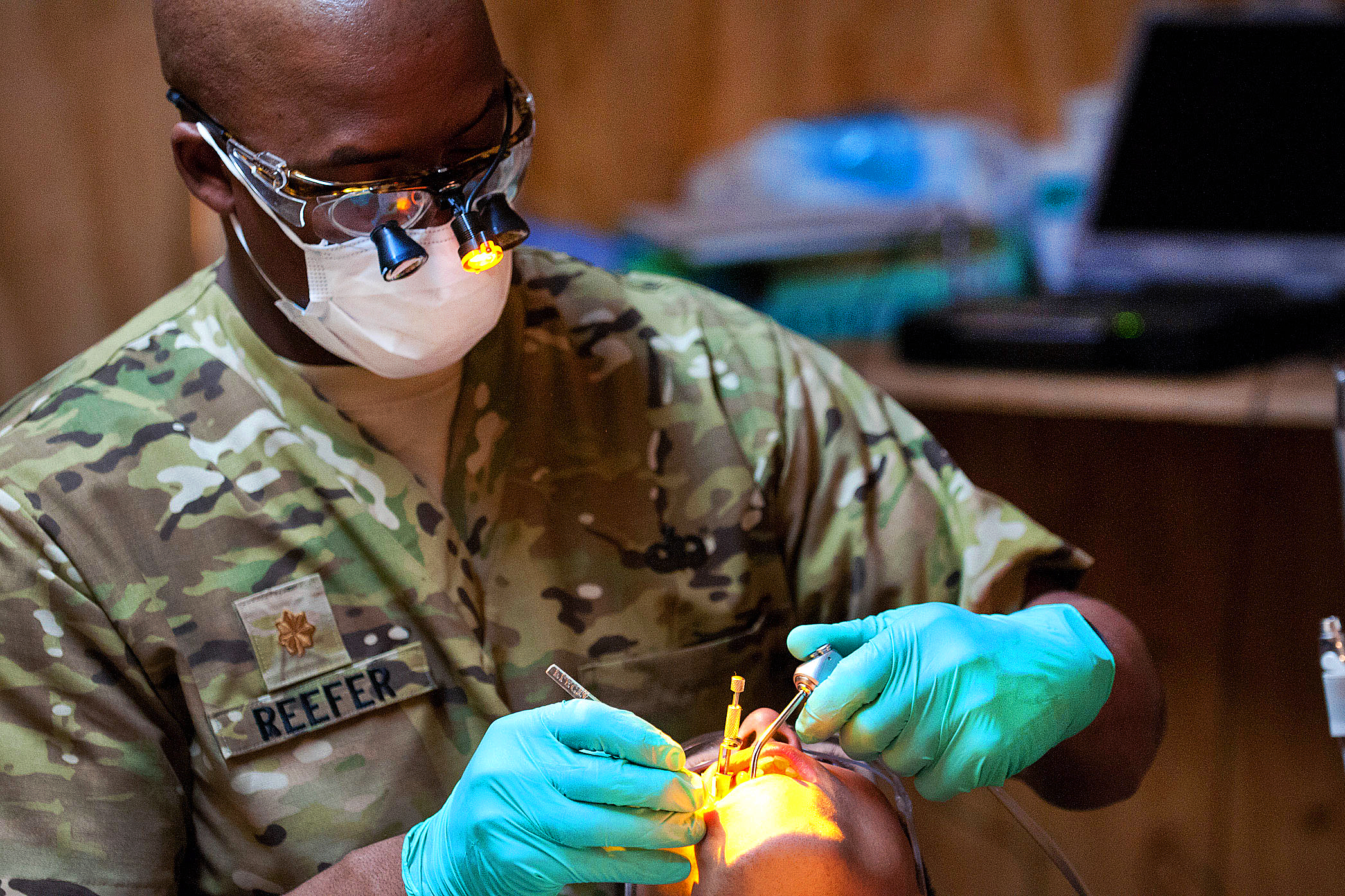 U.S. Army Maj. Murray Reefer applies an instrument to the tooth of a ...