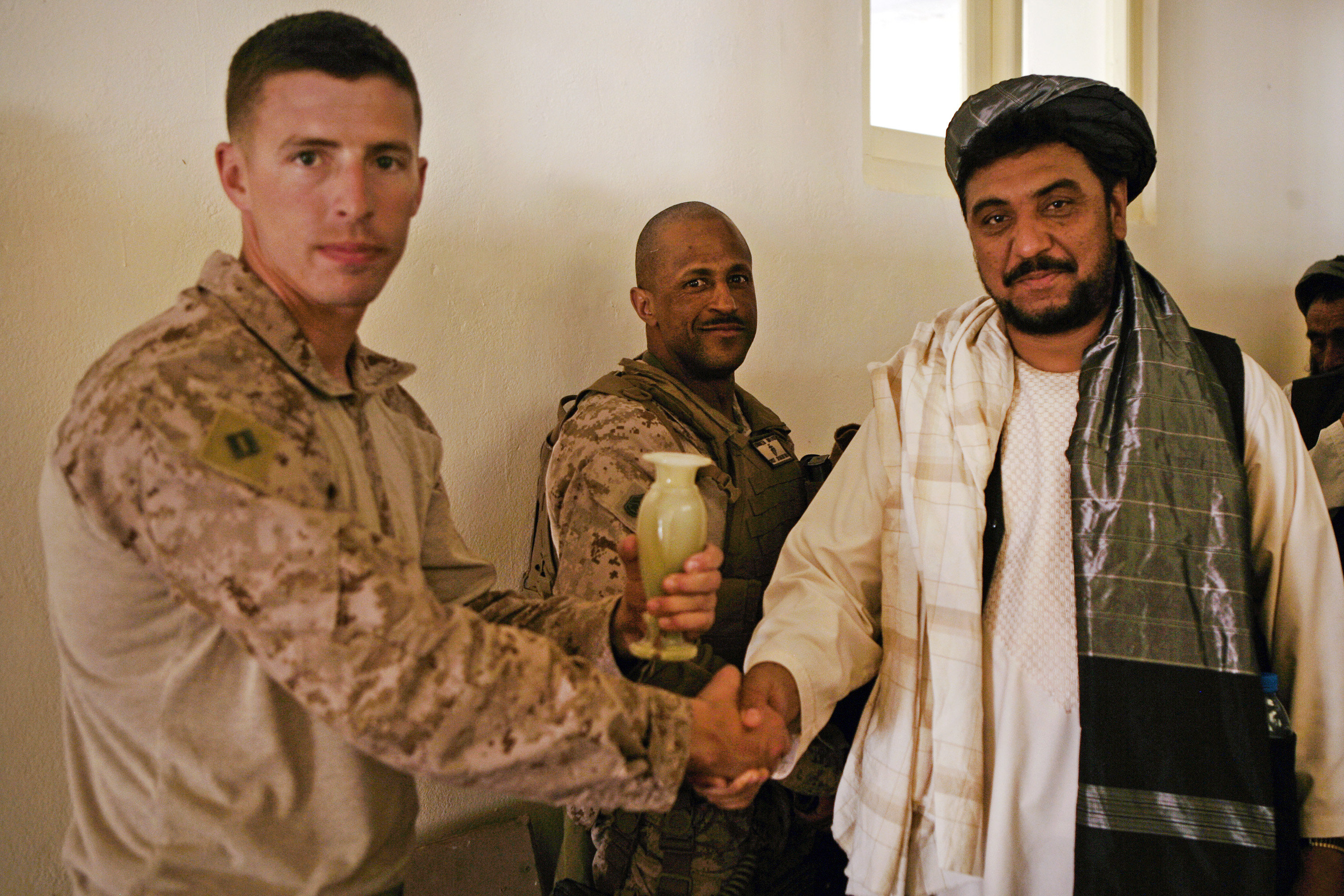 U.S. Marine Corps Capt. Jonathan D. Nixdorf, left, receives a vase from ...