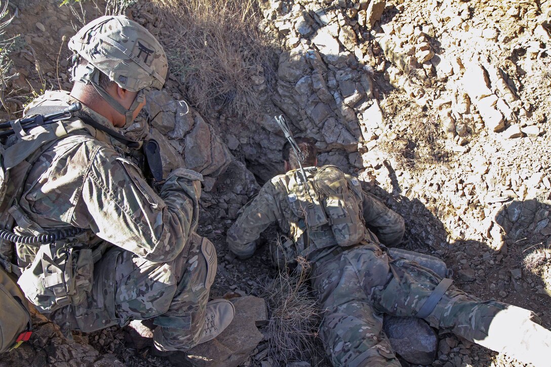 U.S. Army Sgt. Nathan Fleshman, right, investigates a small cave for ...