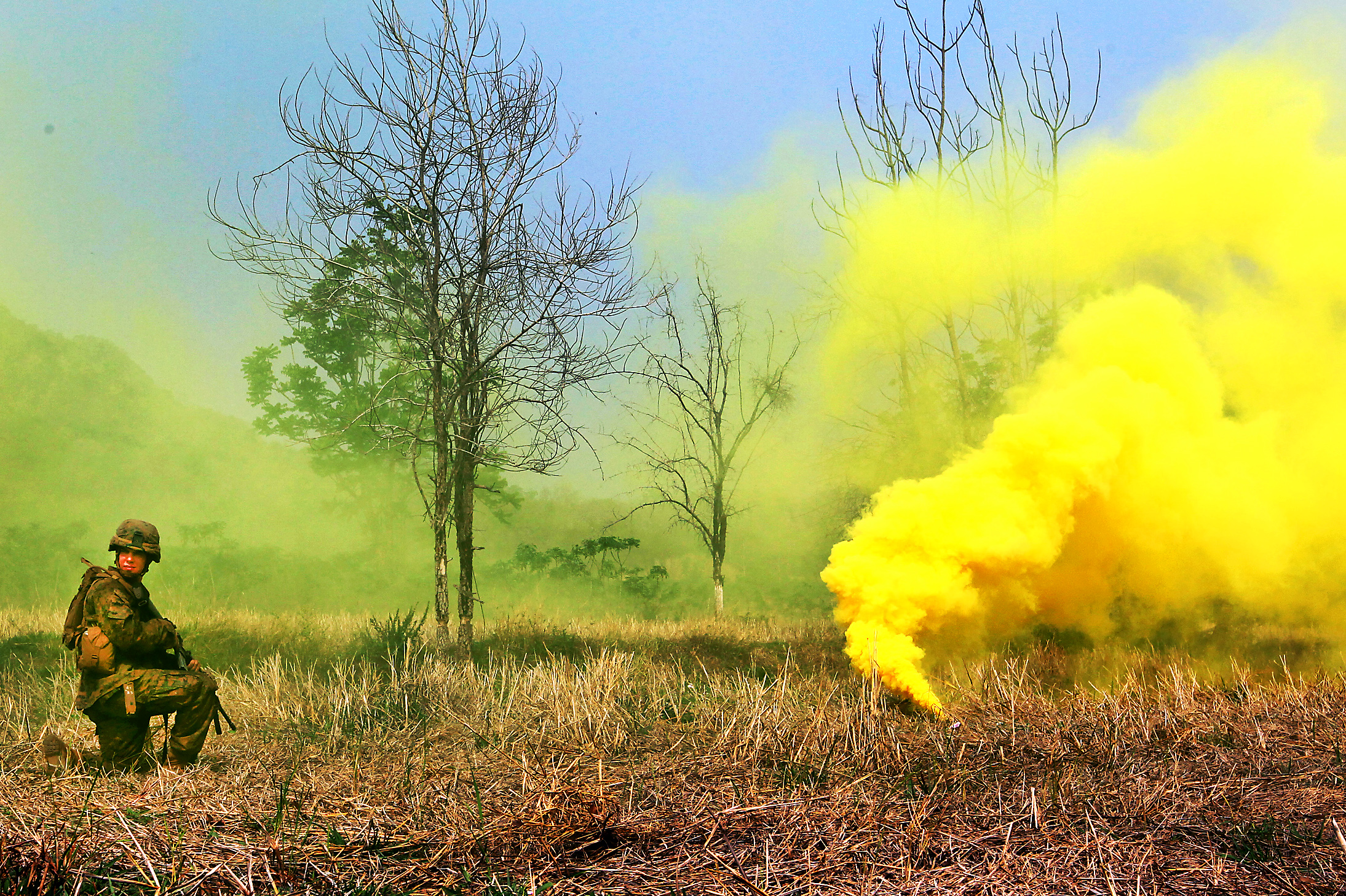 A U.S. Marine provides security as yellow smoke is used to signal to ...