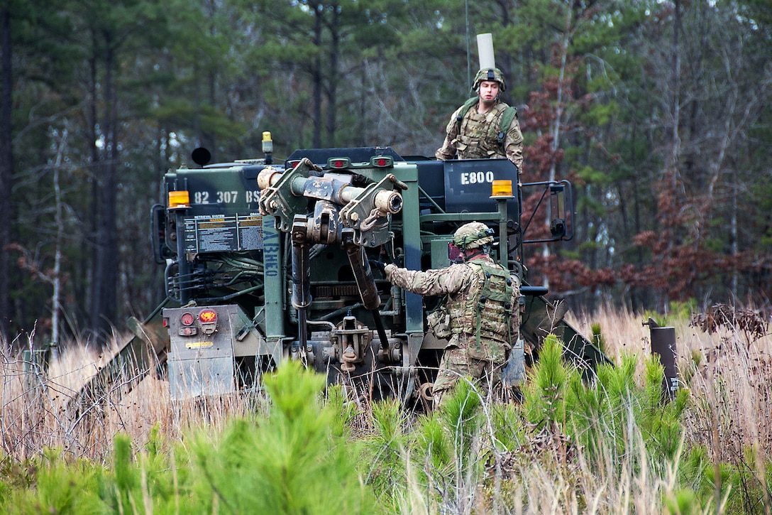 A tactical truck wrecker crew readies a winch to pull two stuck ...
