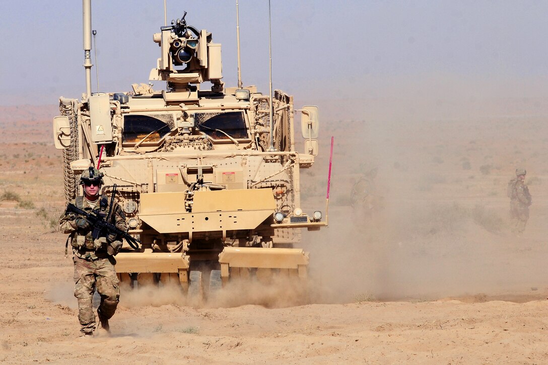 U.S. Army Staff Sgt. Nicholas Amsberry ground guides a mine-resistant ...