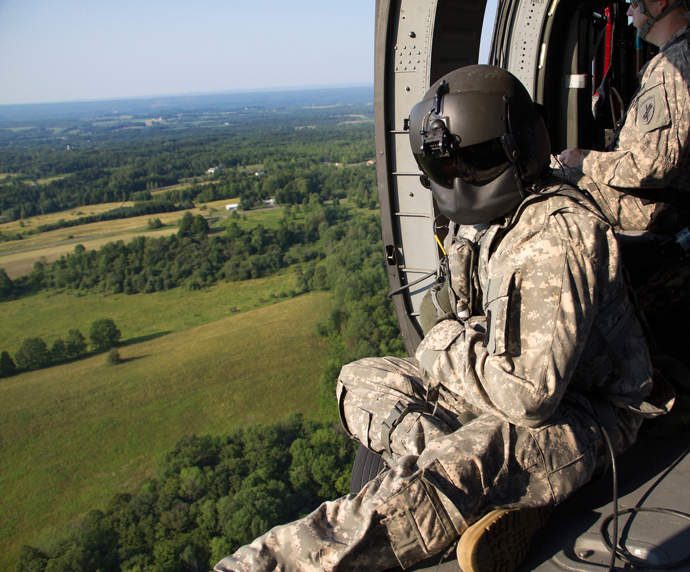 An Army crew chief looks out the door of a UH-60 Black Hawk helicopter ...
