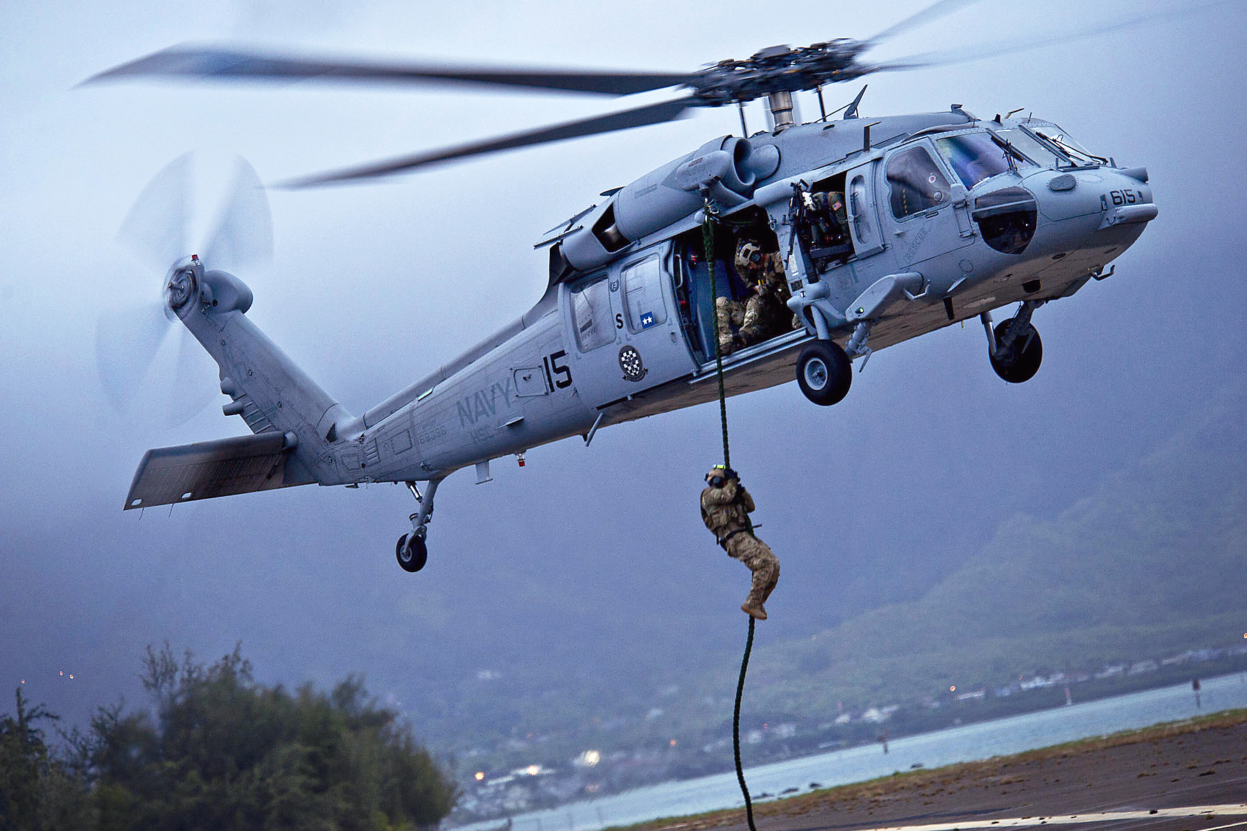 A U.S. sailor fast ropes out of a U.S. Navy MH-60S Night Hawk ...
