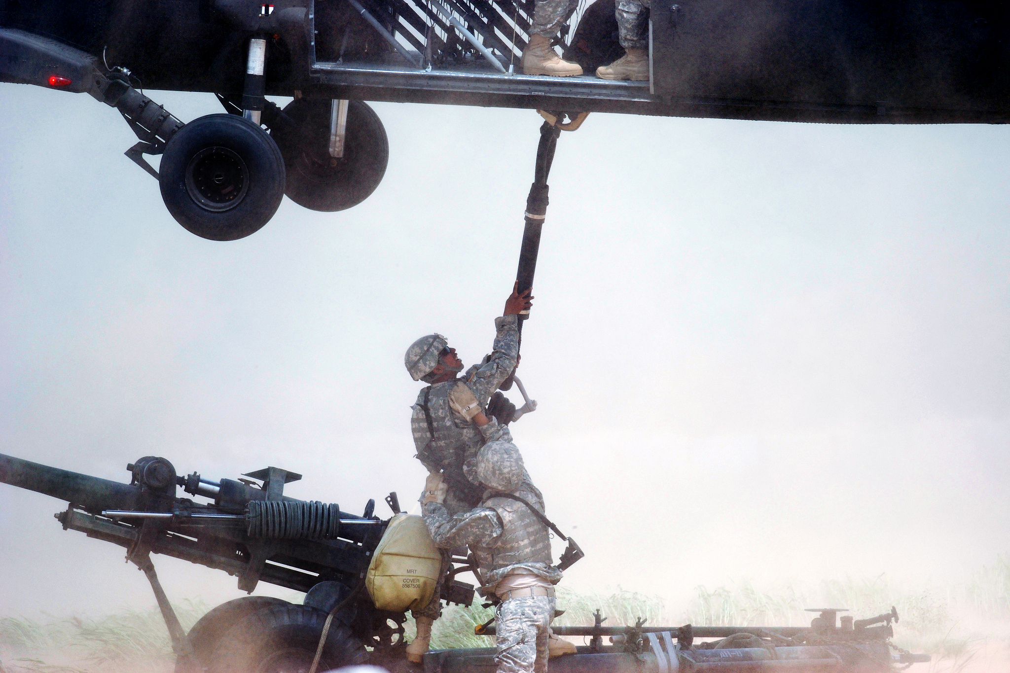 Soldiers hook their 105 mm howitzer to a UH-60 Black Hawk helicopter ...