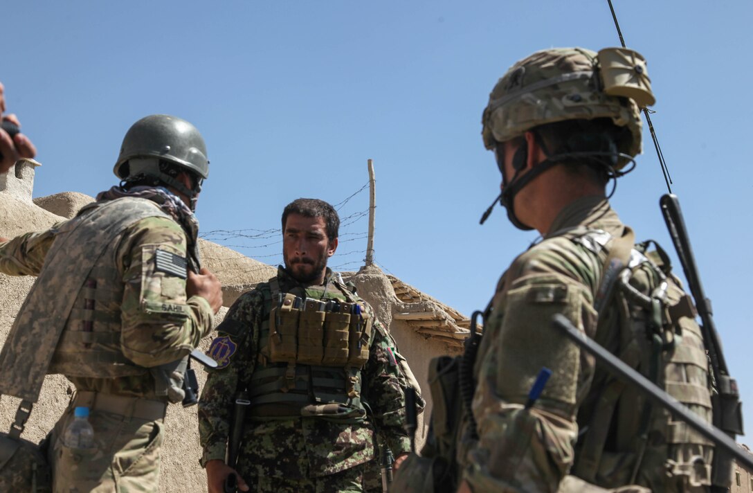 U.S. soldiers and Afghan soldiers talk during a patrol to search for ...