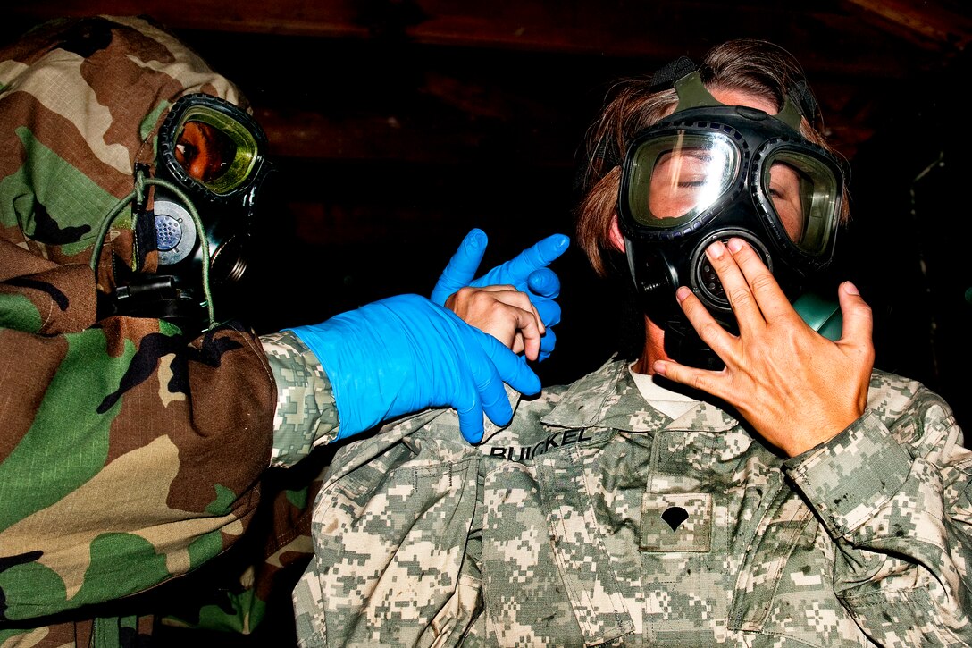 Army Spc. Kristi Buickel, right, breaks the seal of her gas mask ...