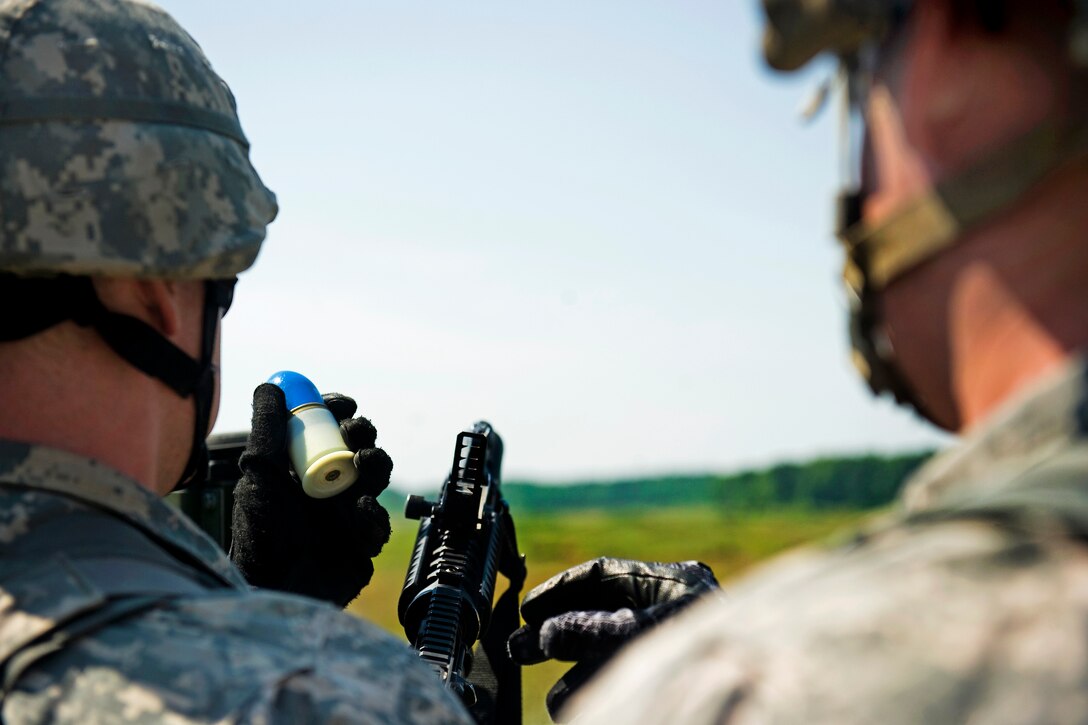 A soldier prepares to load an M203 grenade launcher before firing a ...