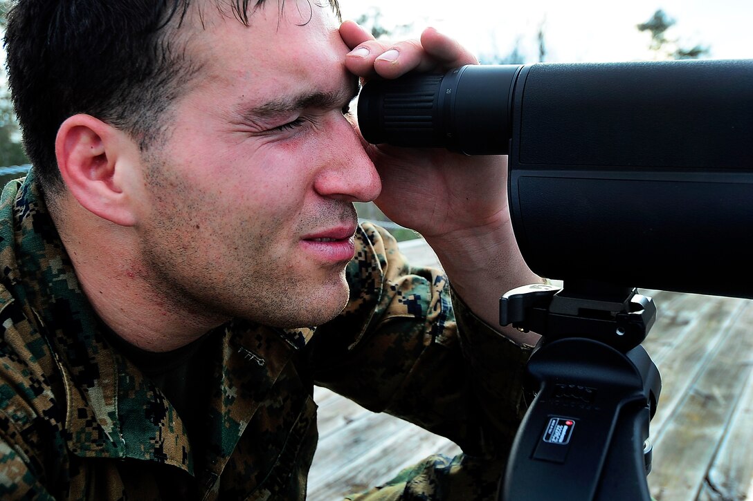 A Marine Corps scout sniper looks through a spotting scope during ...