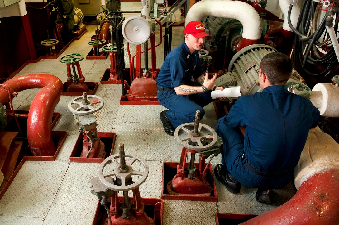 U.S. Navy Petty Officer 1st Class Michael Trosper, left, briefs a ...