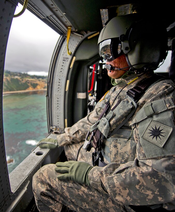 Army Sgt. Greg Fernandez scans his surroundings during a flight ...
