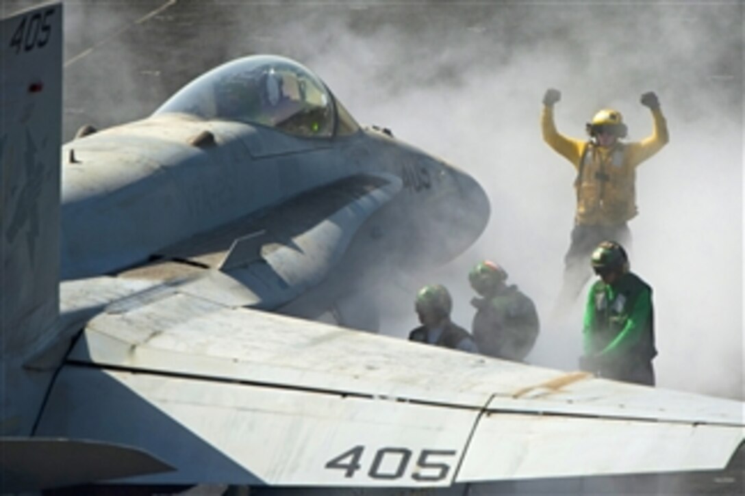 Petty Officer 3rd Class Eric Welsh directs an F/A-18C Hornet onto the ...