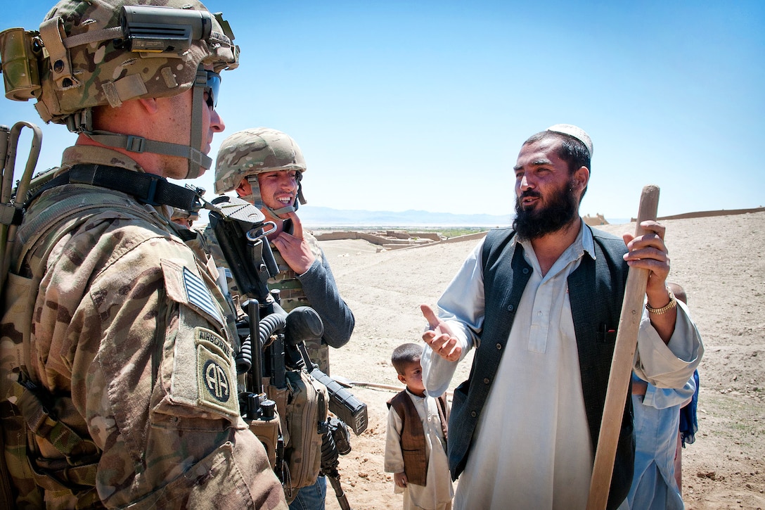 U.S. Army Capt. Tyler Vest, left, listens as a villager says in English ...