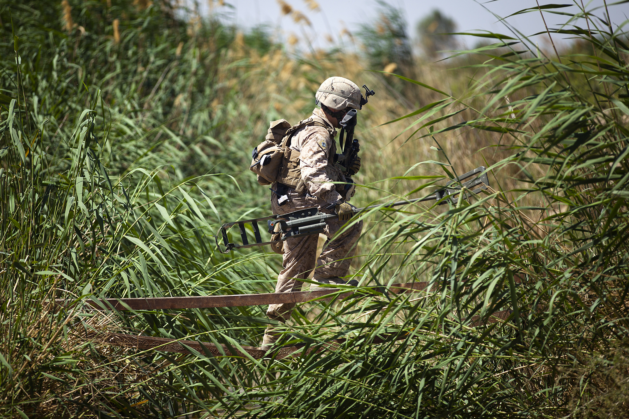 U.S. Marine Lance Cpl. Andrew Loggins, uses a makeshift bridge to cross ...