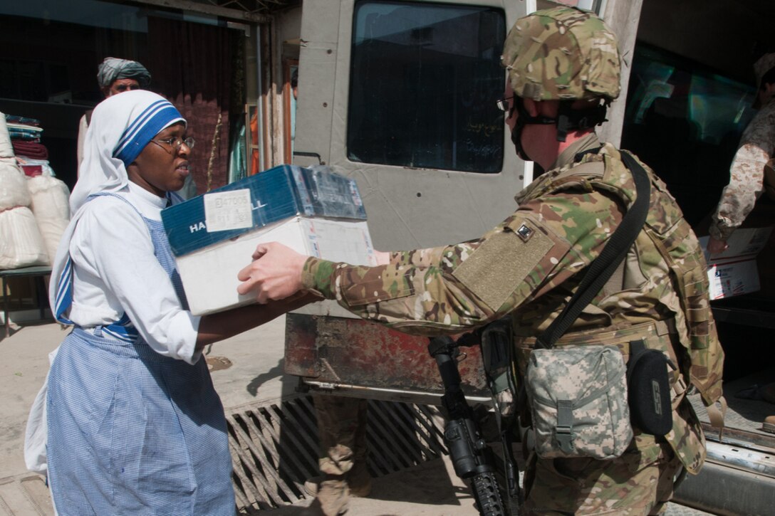 A U.S. servicemember gives a donation to a mother Teresa nun at an ...