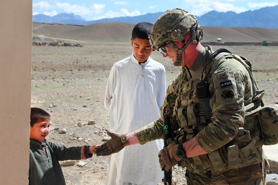 U.S. Army Staff Sgt. Brian Felker offers his hand to an Afghan child at ...
