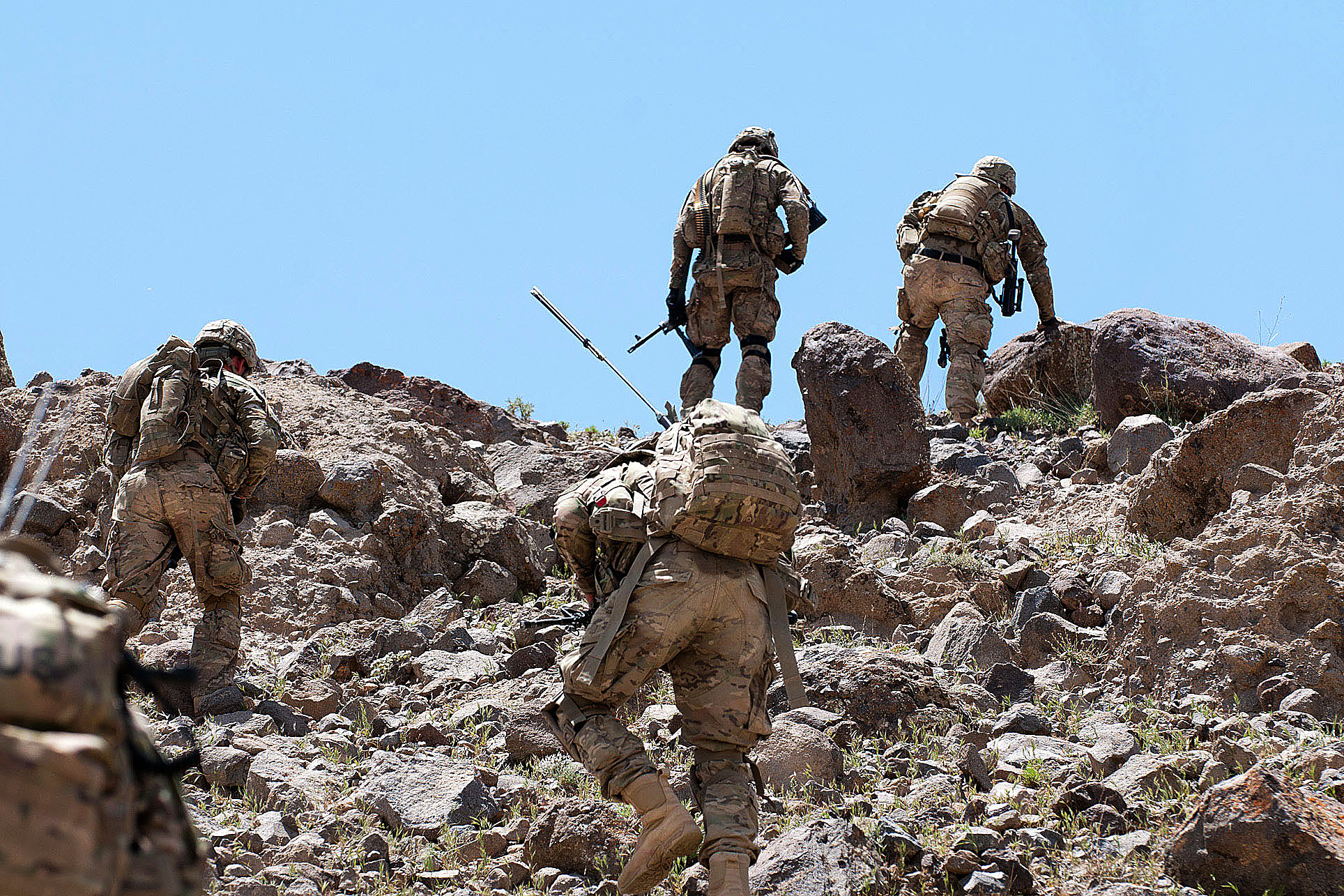 U.S. Army paratroopers climb a steep hill to establish an observation ...