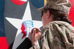 Army Spc. Cassandra Butkos paints the 2nd Infantry Division’s ...