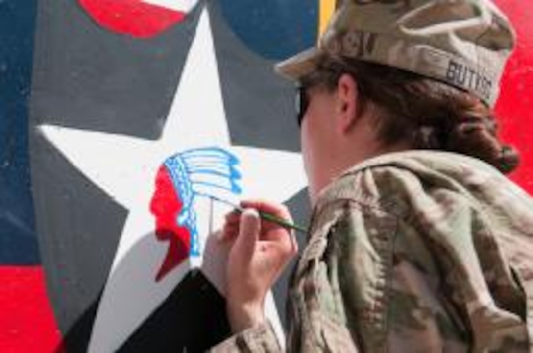Army Spc. Cassandra Butkos paints the 2nd Infantry Division’s ...