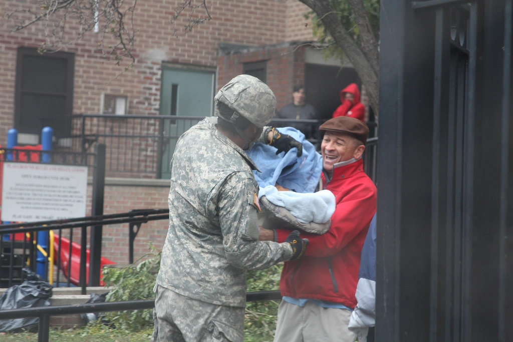A soldiers assists a man and child displaced by Hurricane Sandy in ...