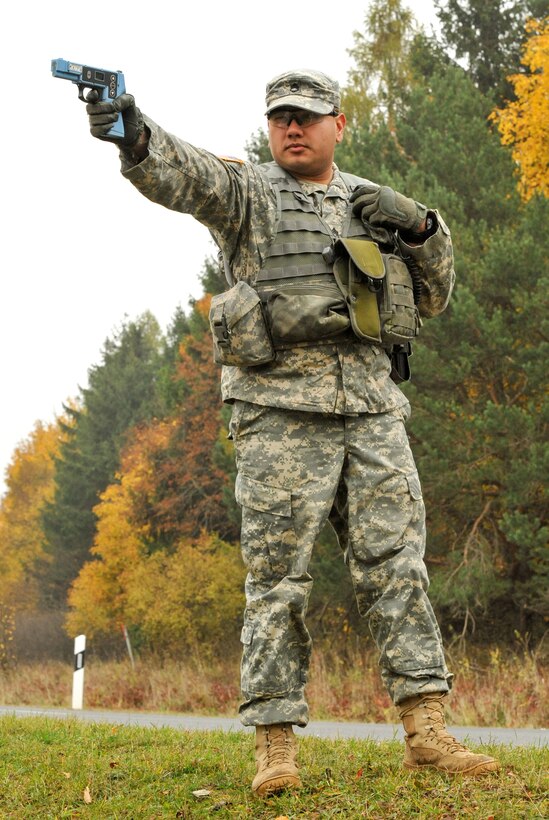 A U.S. Army observer-controller points a laser controller gun at a hit ...