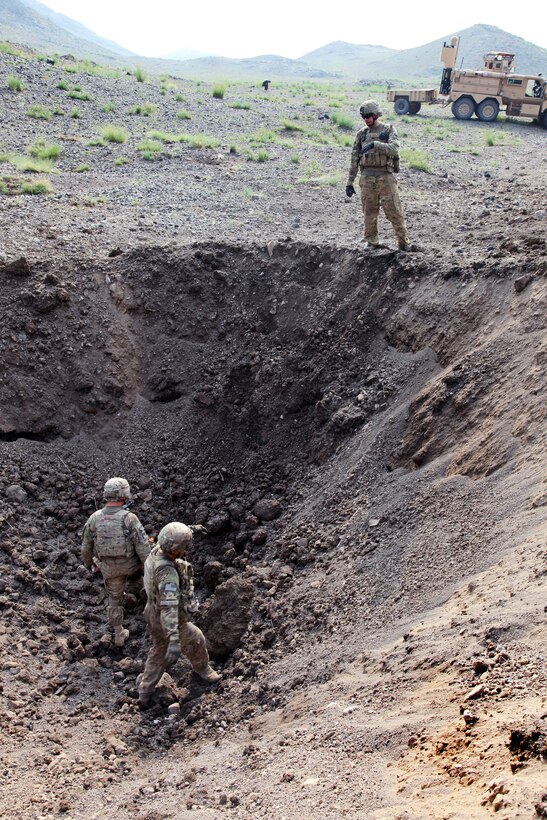 U.S. soldiers stand in a new crater at the demolition range on Forward ...