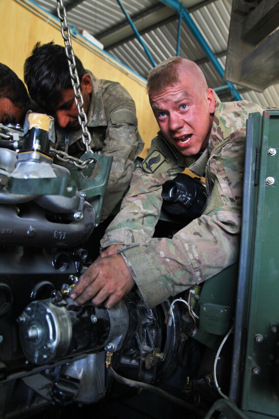 U.S. Army Pvt. Rodger Pendergrass and Afghan soldiers place an engine ...