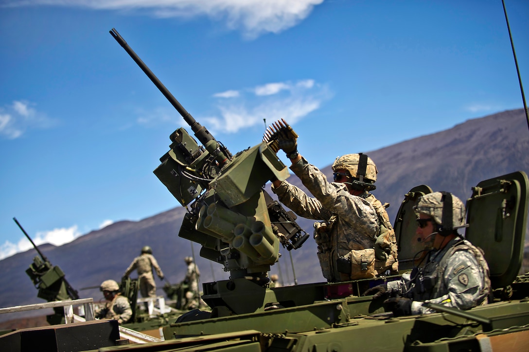 Army Spc. Warren Feeley, left, loads ammunition into the .50-caliber ...