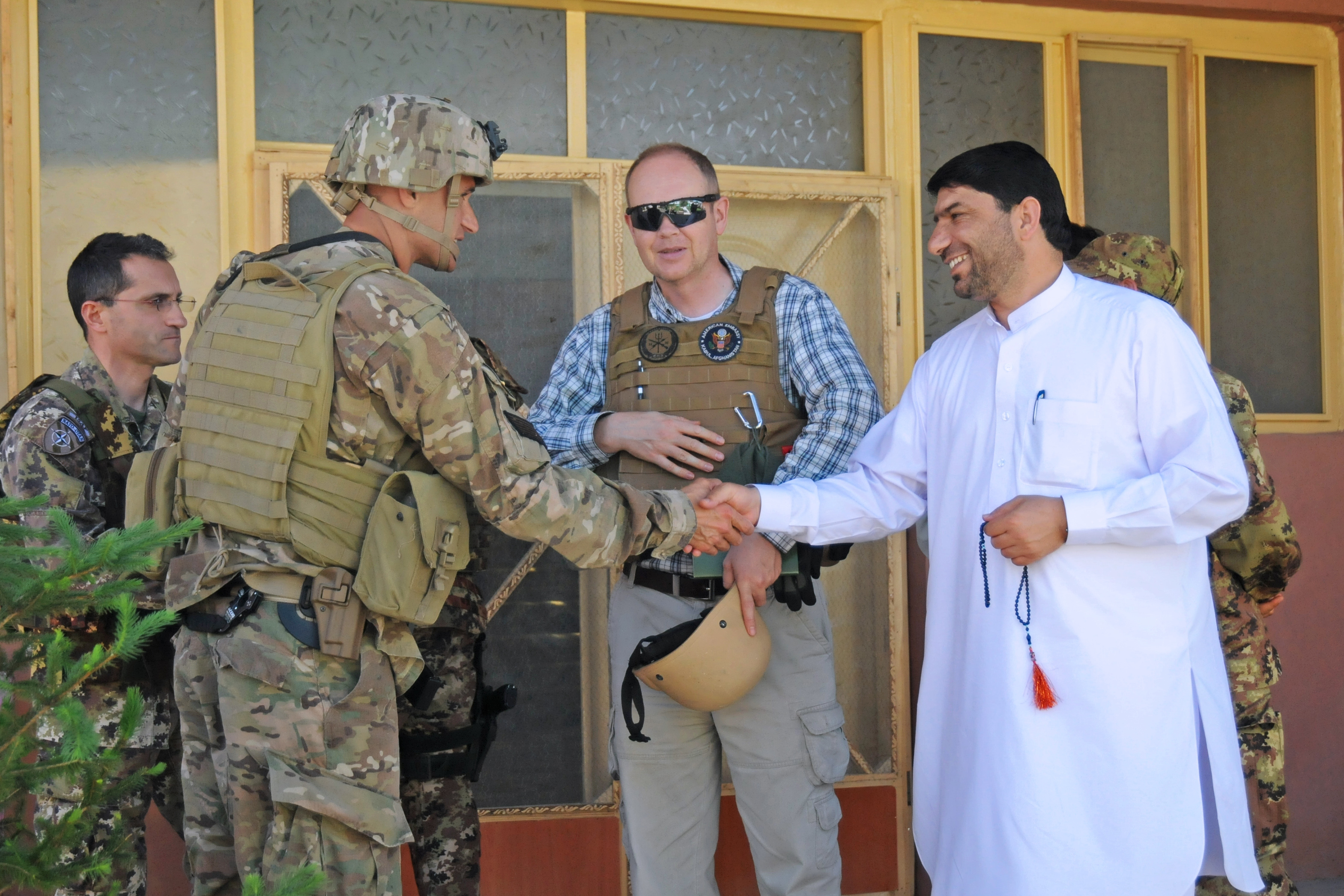U.S. Navy Cmdr. Louis McCray, left, shakes hands with Mohammed Akram ...