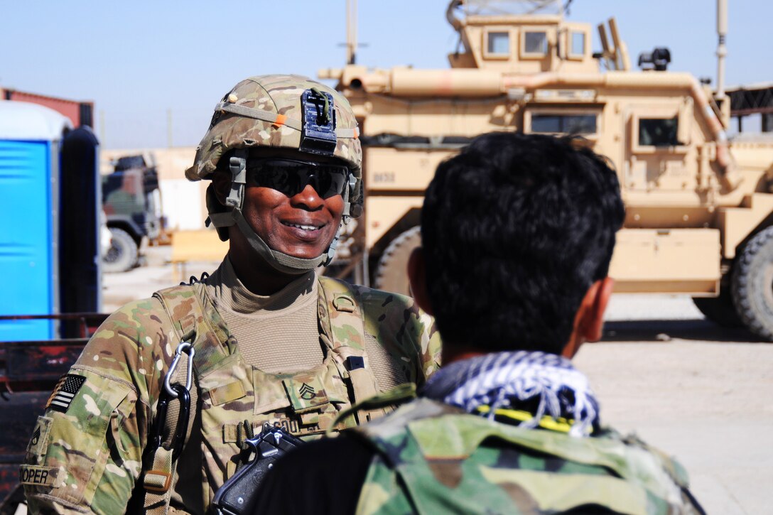 U.S. Army Staff Sgt. Roderick Cooper, left, talks with a team linguist ...