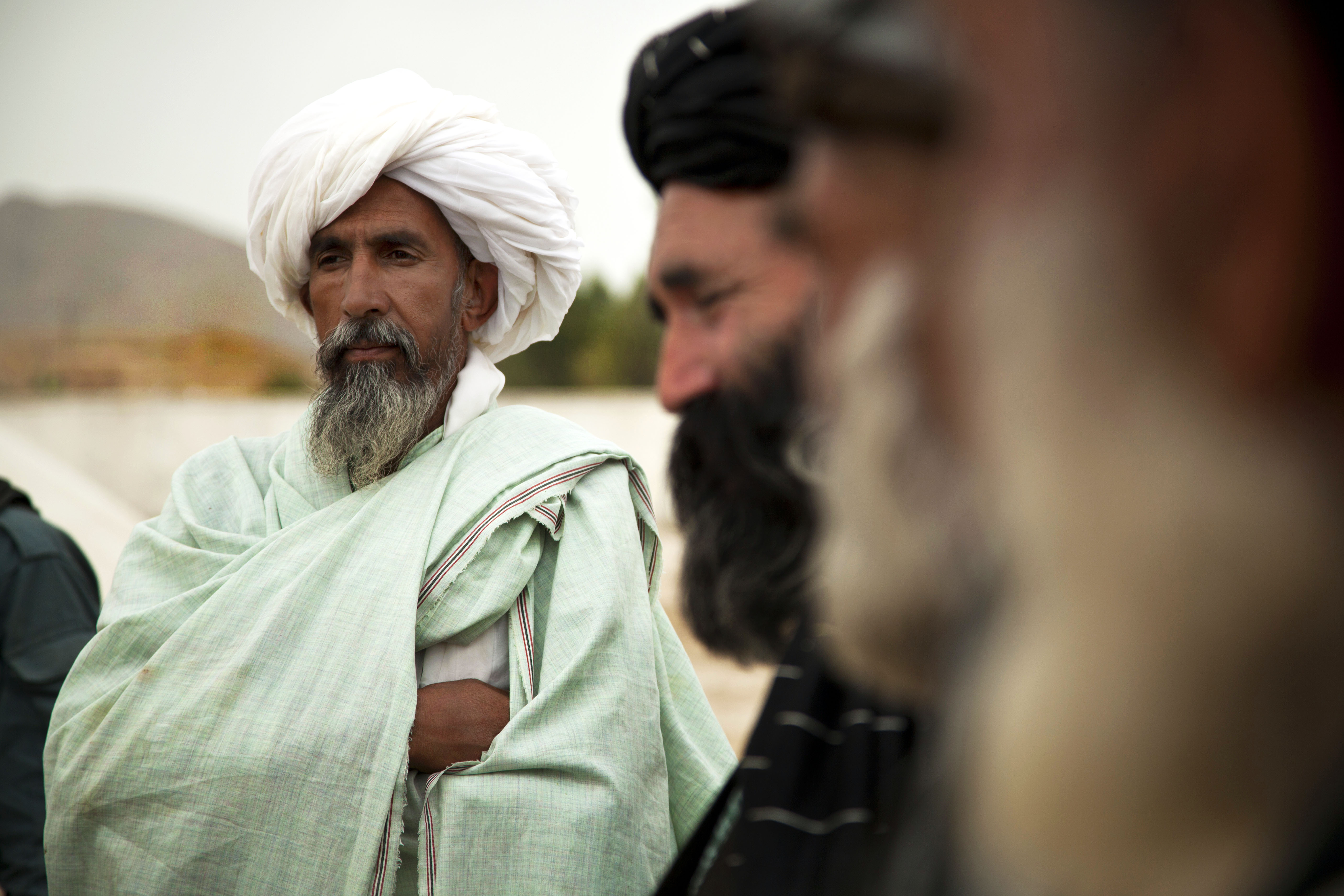 Villagers listen as a coalition force member speaks with the district ...