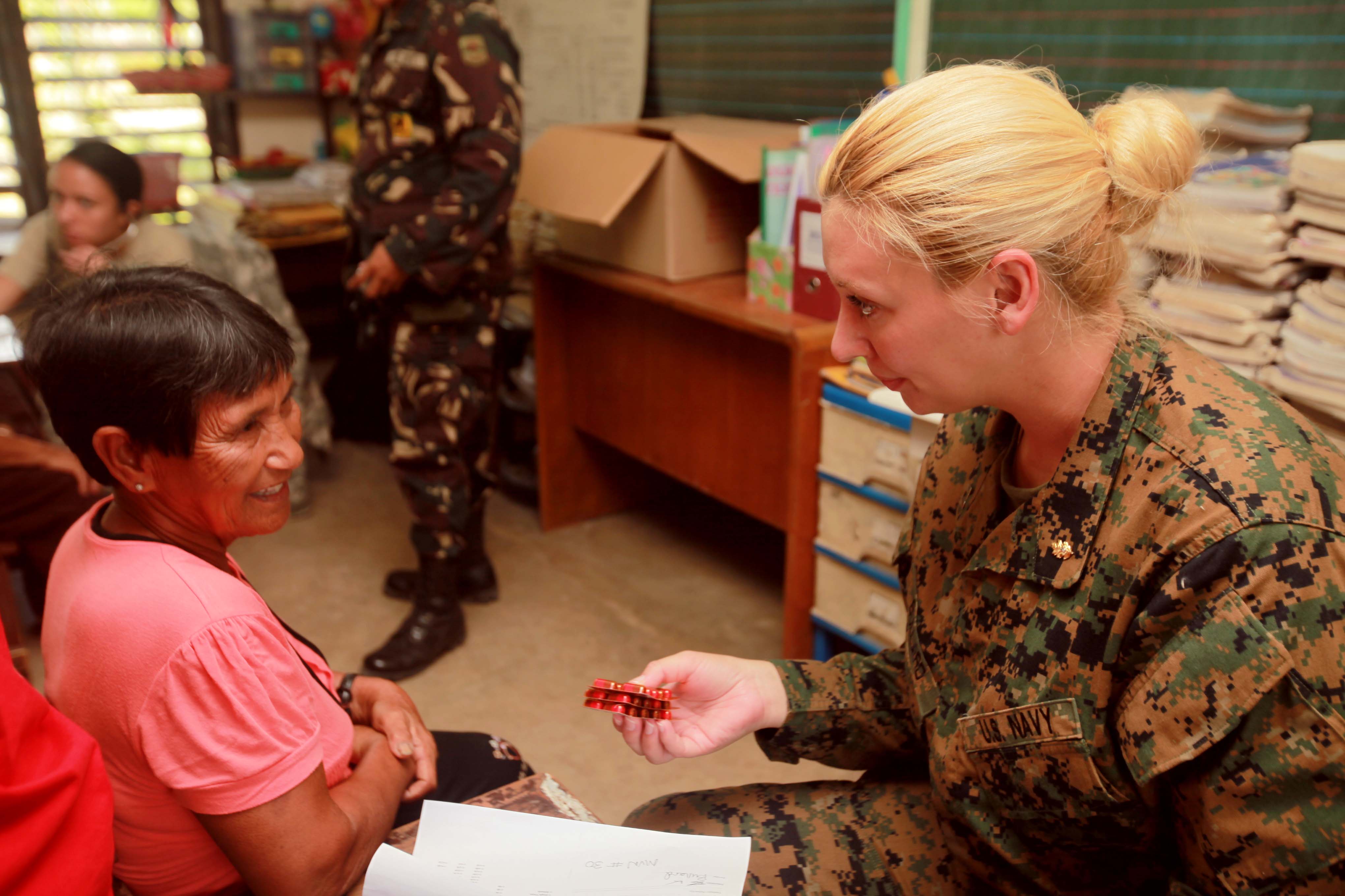 U.S. Navy Lt. Susan Bullard gives an elderly woman multivitamins during ...