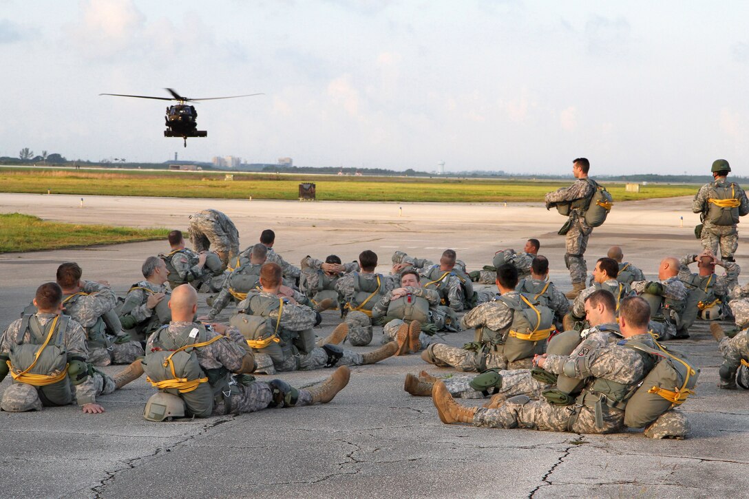 Soldiers wearing their MC-6 parachutes watch as a MH-60 Black Hawk ...