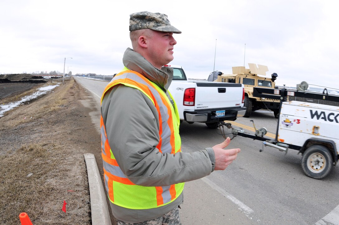 Army Spc. Bryan Sholts directs a vehicle through a traffic control ...