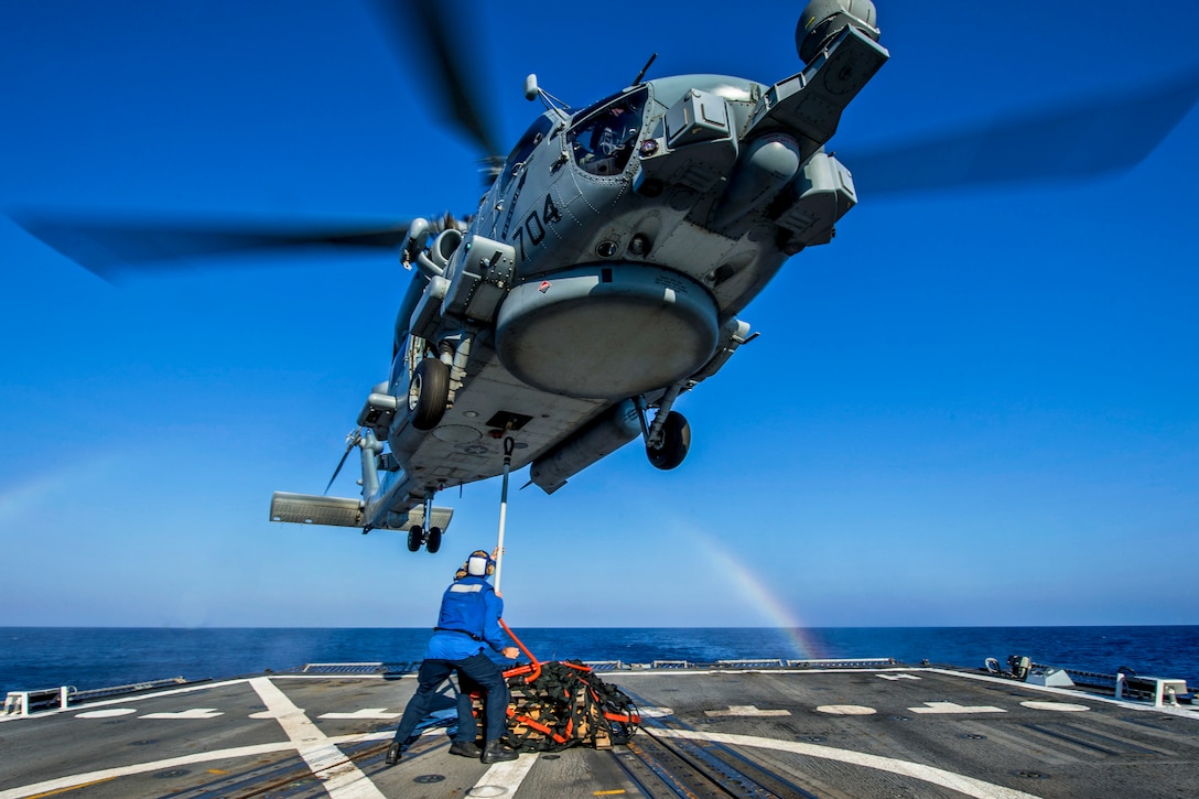 U.S. sailors hook cargo to an MH-60R Seahawk helicopter during vertical ...