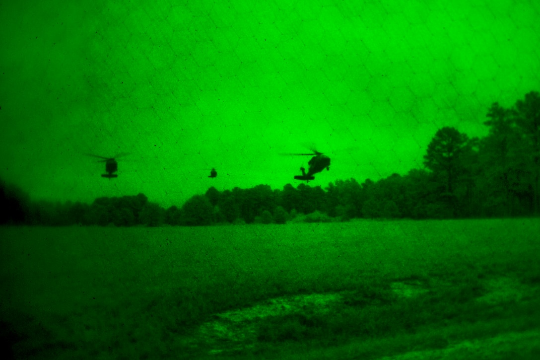As seen through a night-vision device, Army UH-60 Black Hawk ...
